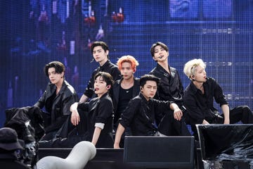 seven performers in black outfits posing during a stage performance