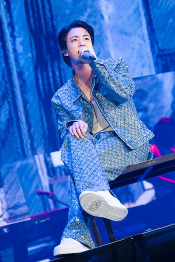a performer styled in a fashionable outfit during a live event
