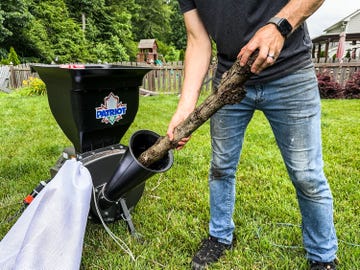 a person putting a thick branch into a patriot products 5 hp corded electric wood chipper