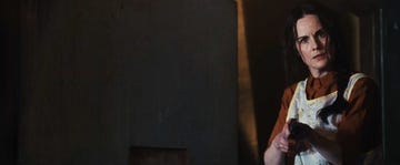 michelle dockery holding a small firearm in a dimly lit room in a scene from please don't feed the children