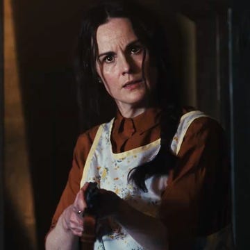 Please Don't Feed The Children Official Trailer .jpg michelle dockery holding a small firearm in a dimly lit room in a scene from please don't feed the children
