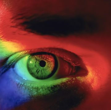 rainbow colors projected onto a mans face where we see a close up of the right eye and eyebrow only